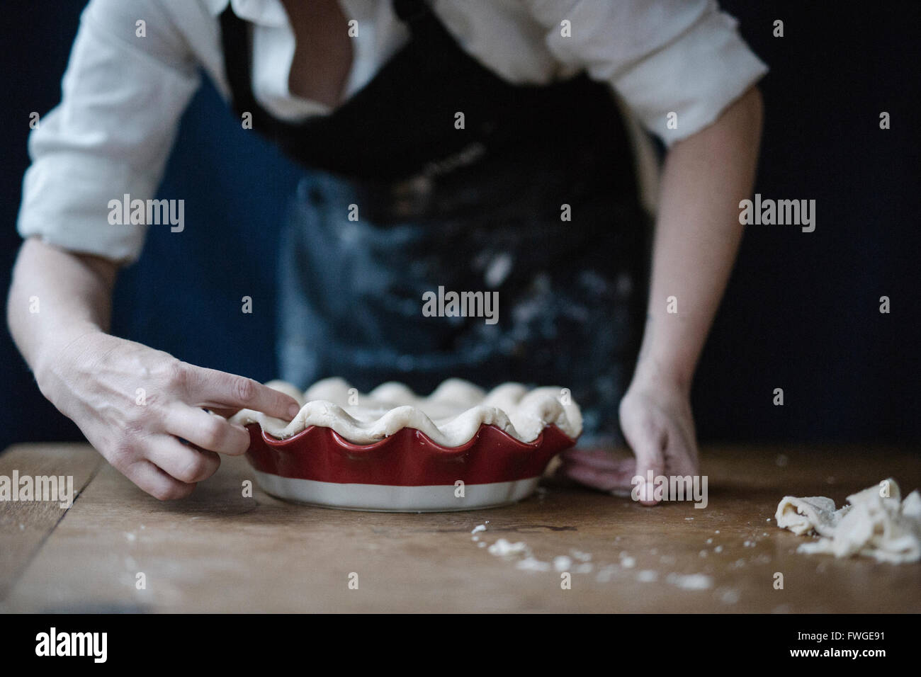 A woman in a kitchen decorating the pastry top of a home made pie Stock ...