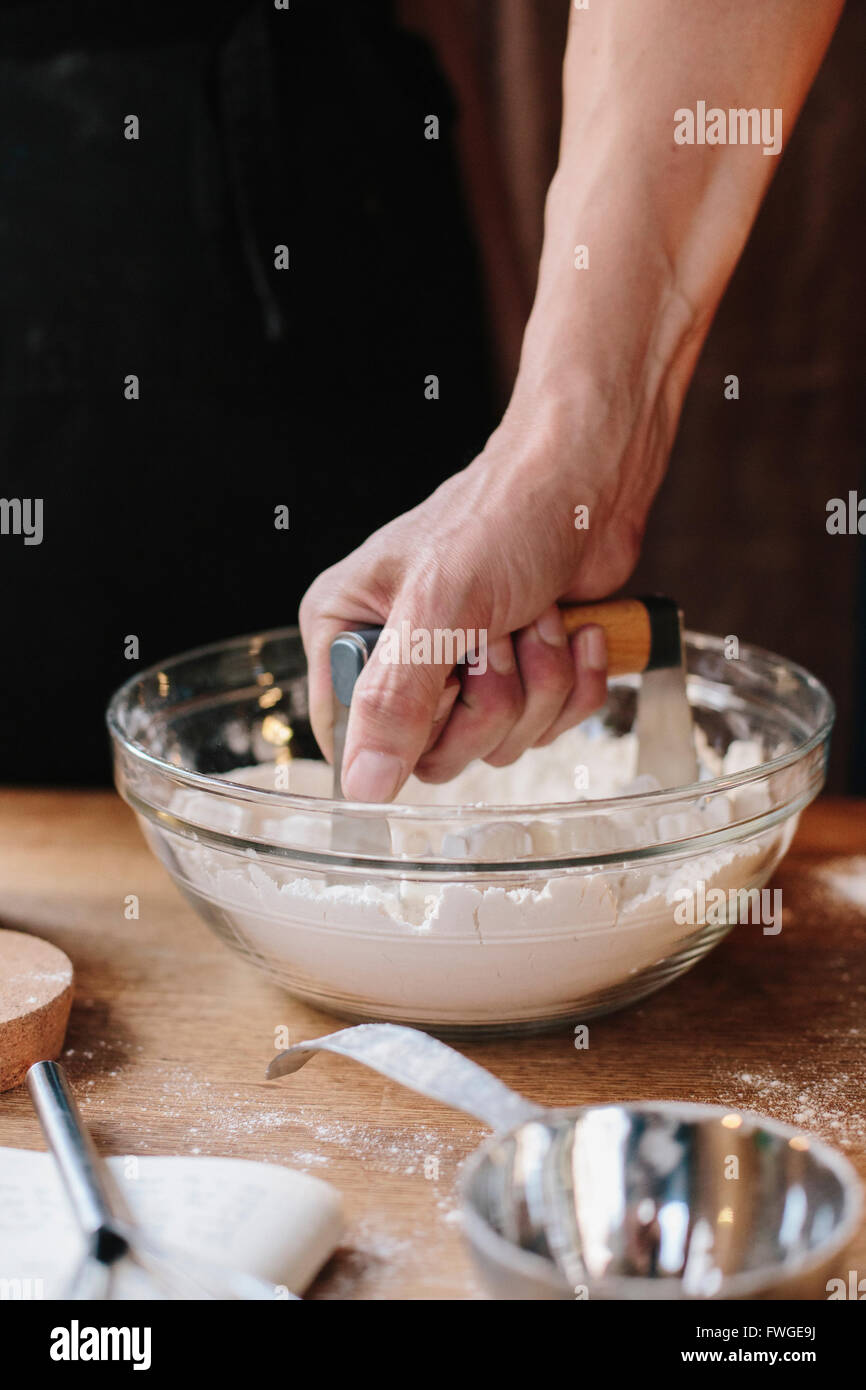 A person using a masher to soften butter in a bowl and mix pastry Stock ...