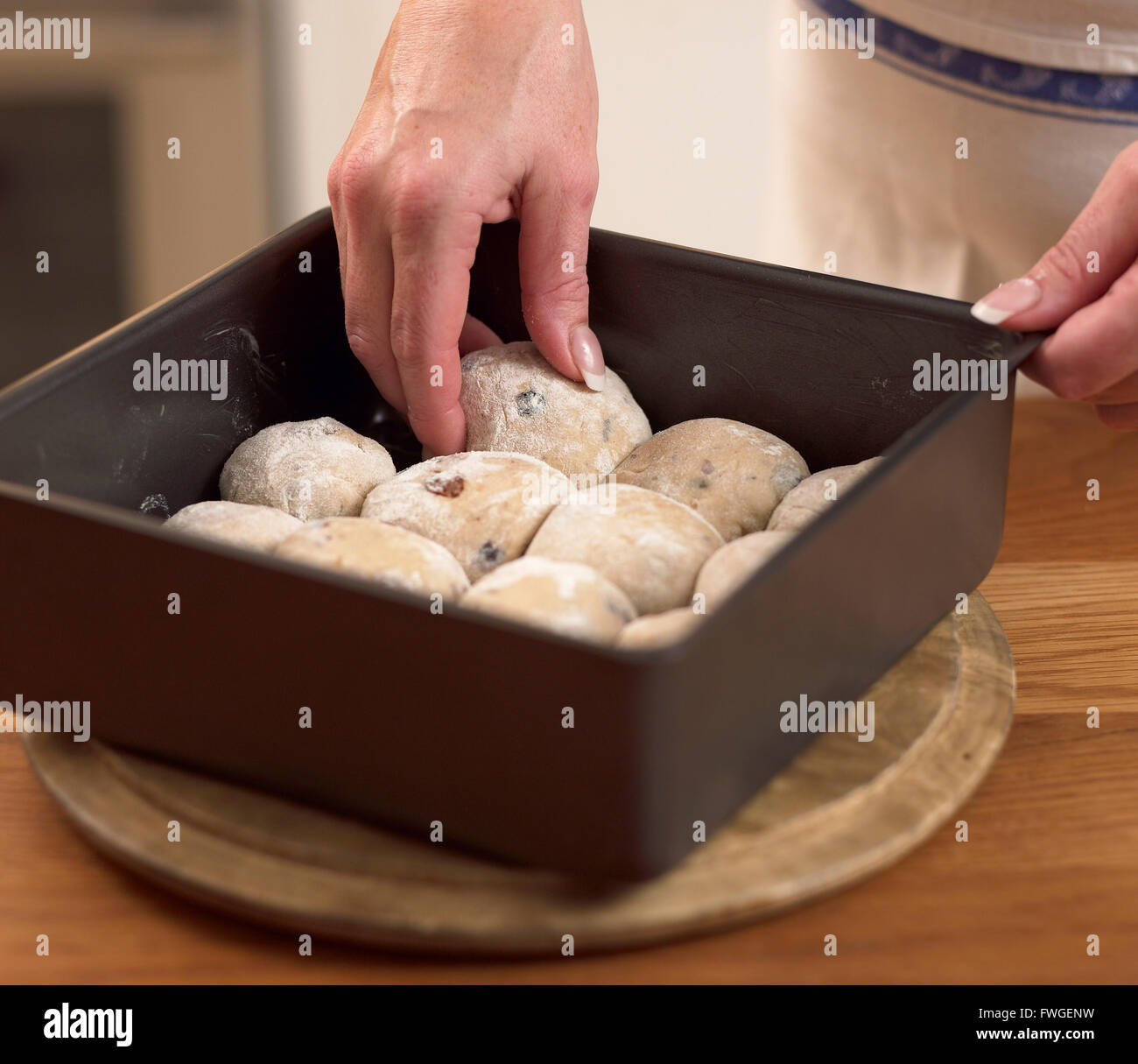 Placing buns in a baking tray ready to place in the oven Stock Photo ...