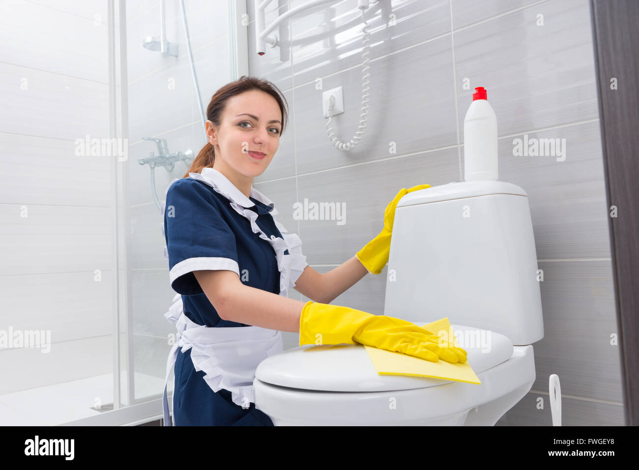 Smiling attractive housekeeper or housewife wearing a neat white apron ...