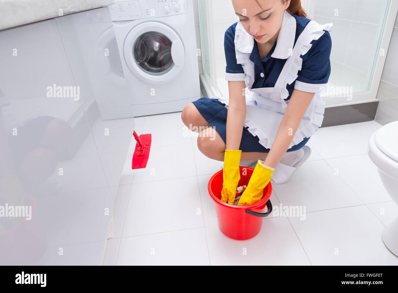 Housekeeper changing the cloth on the colorful red mop wringing out the ...