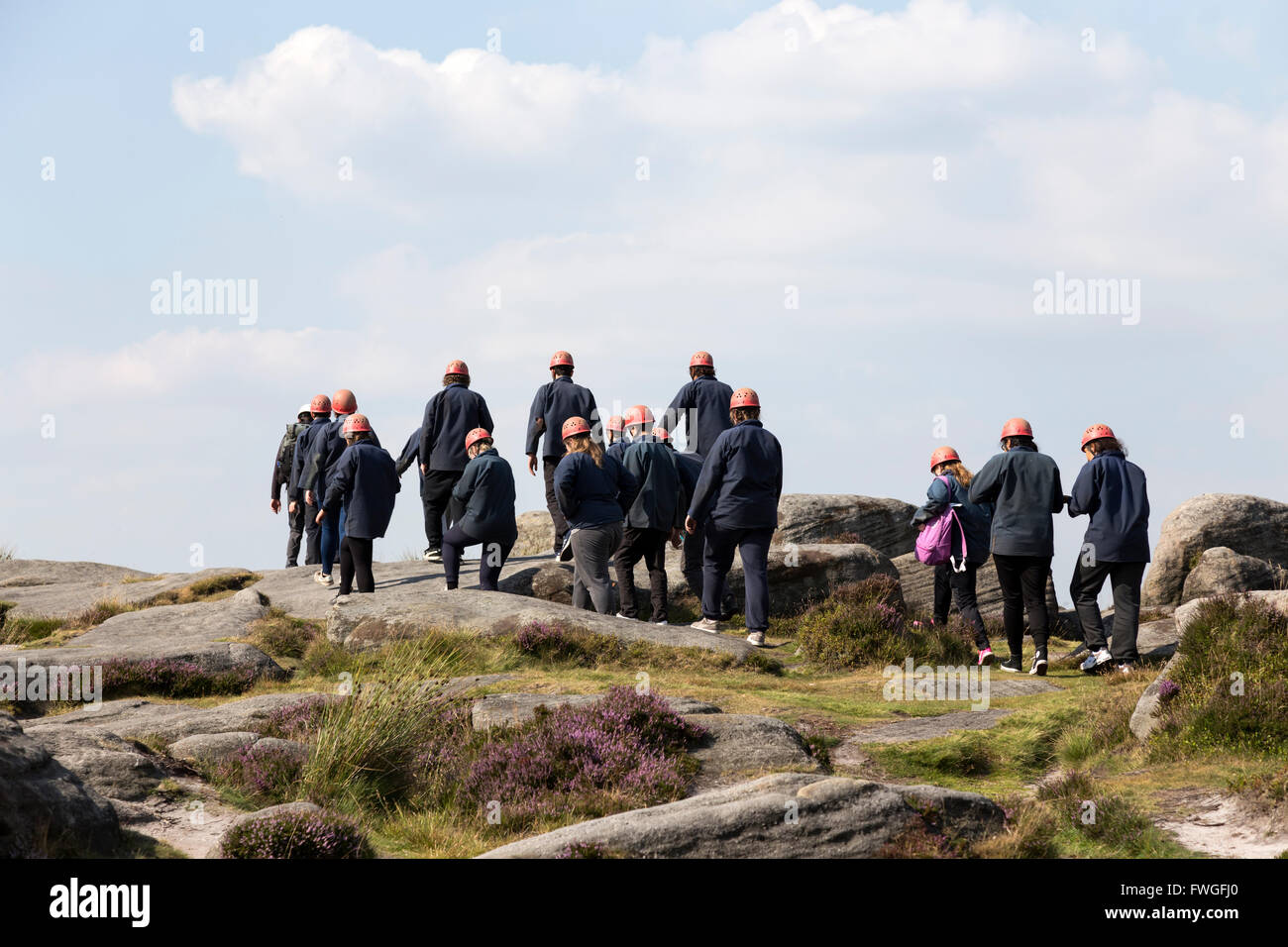 Group of young people wearing red helmets in the Peak District National ...