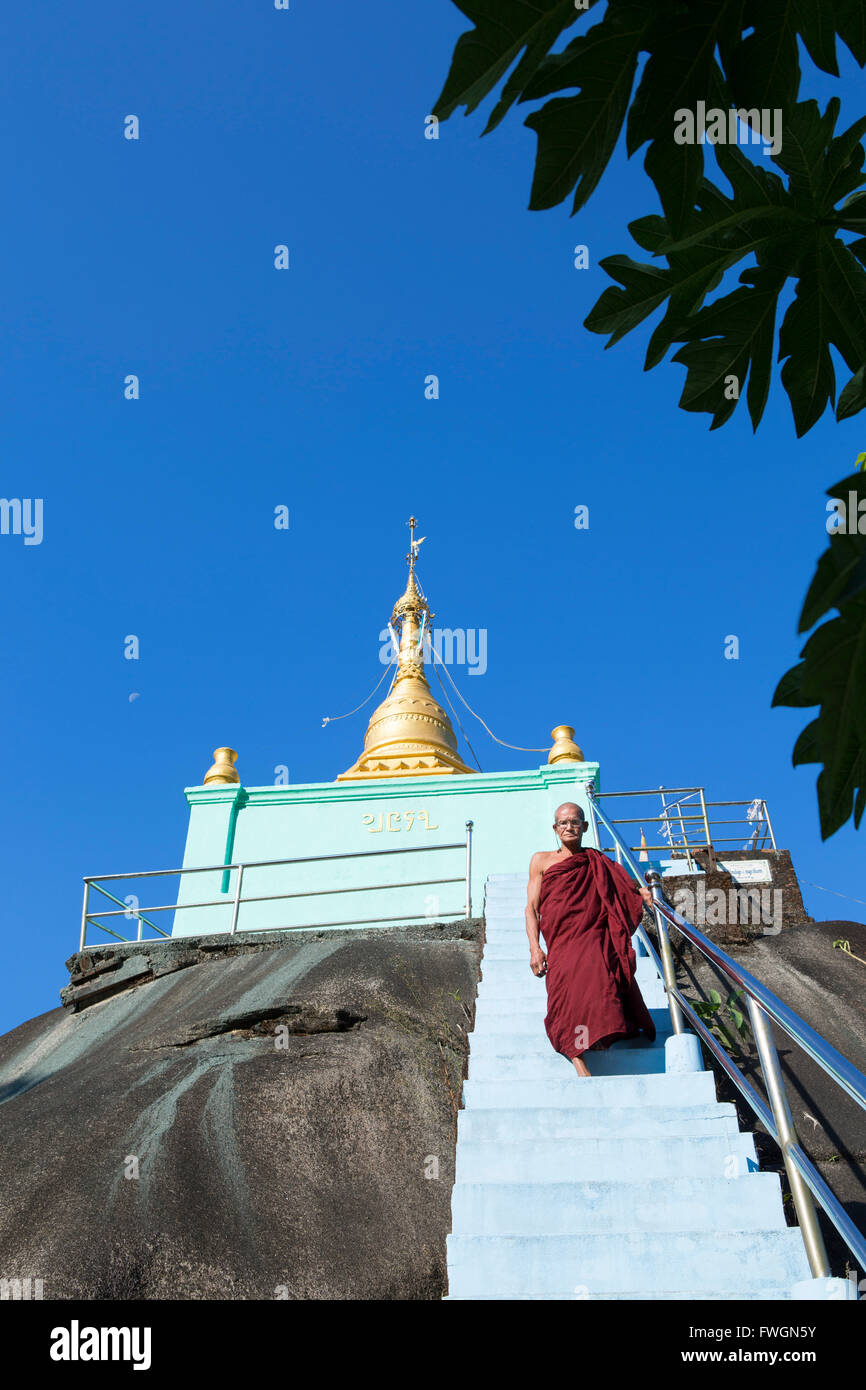 Giant boulder topped by a golden stupa looked after by a buddhist monk ...