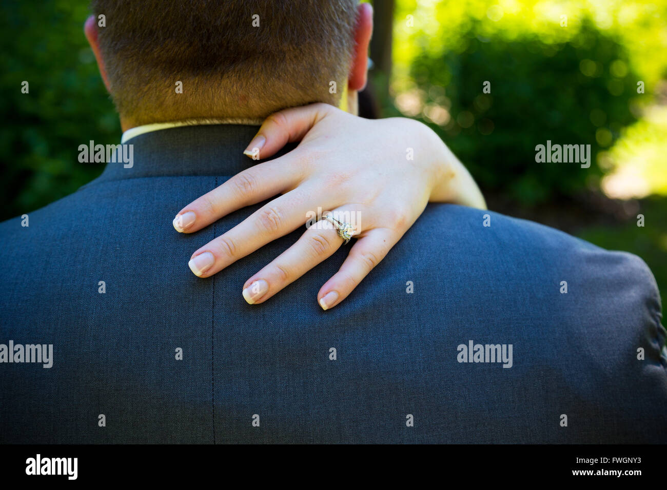 The bride puts her hand over the shoulder of the groom while dancing to ...