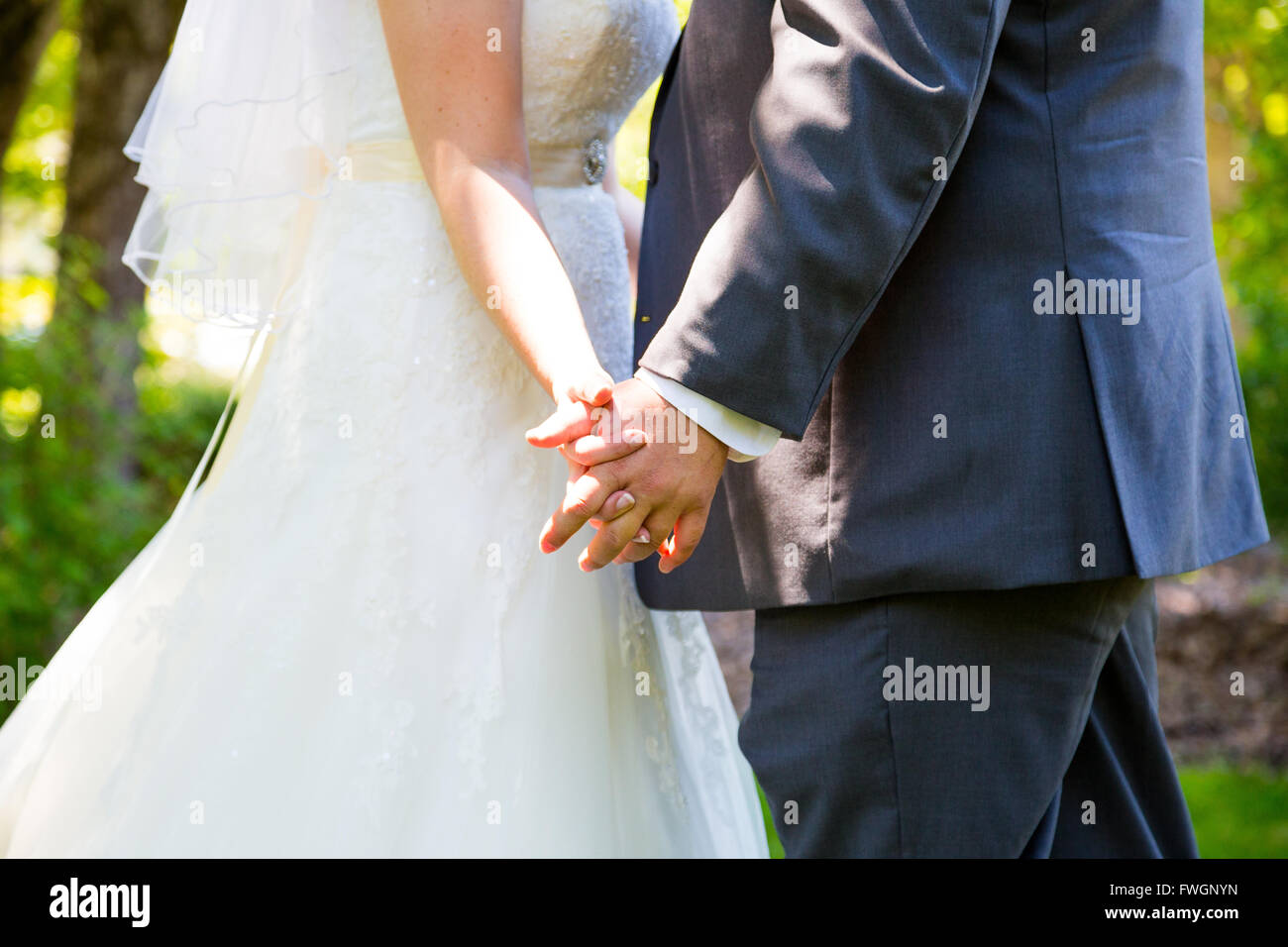This bride and groom hold hands romantically while kissing on their ...