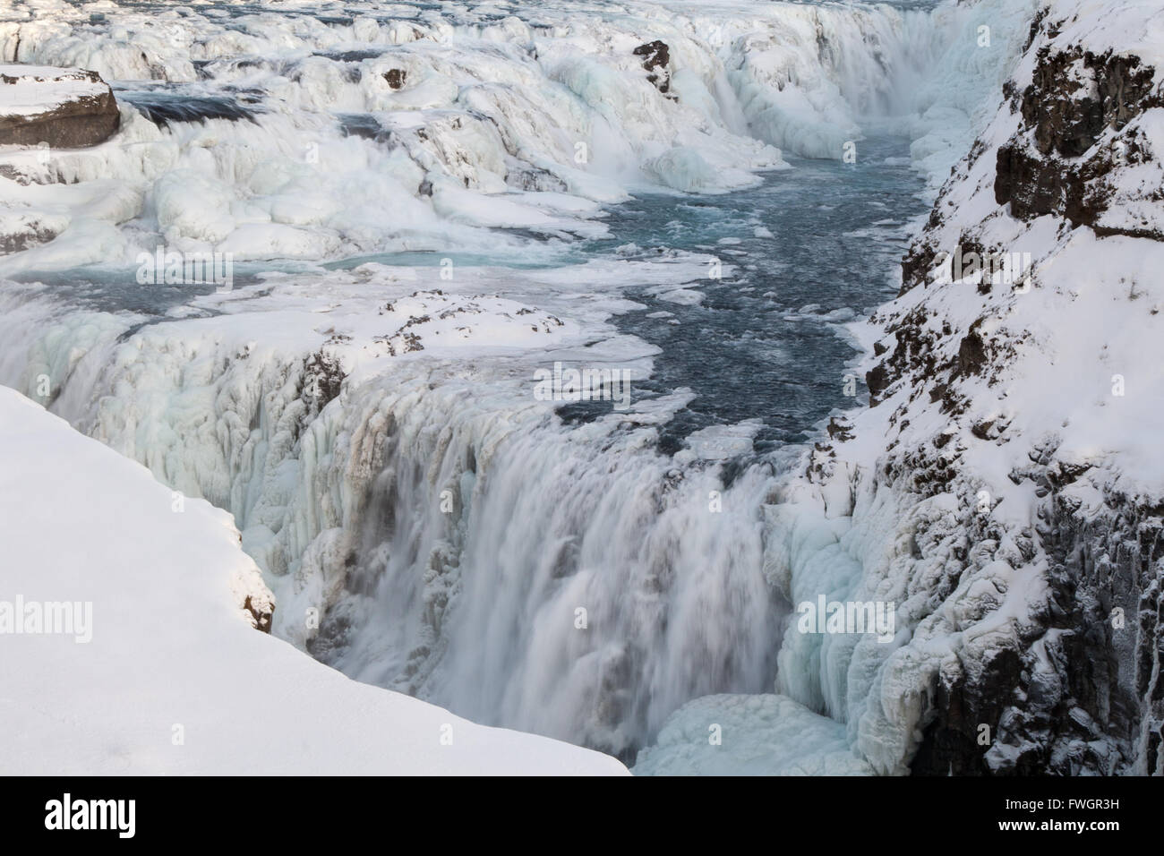 Close up of water flowing over Gulfoss waterfalls surrounded by snow ...