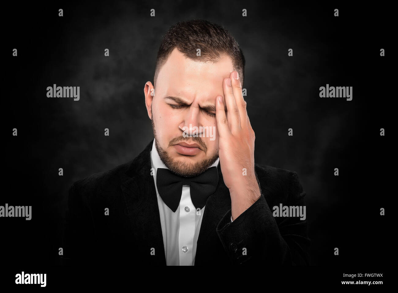 Young man holding his head feeling a headache or intensely thinking ...