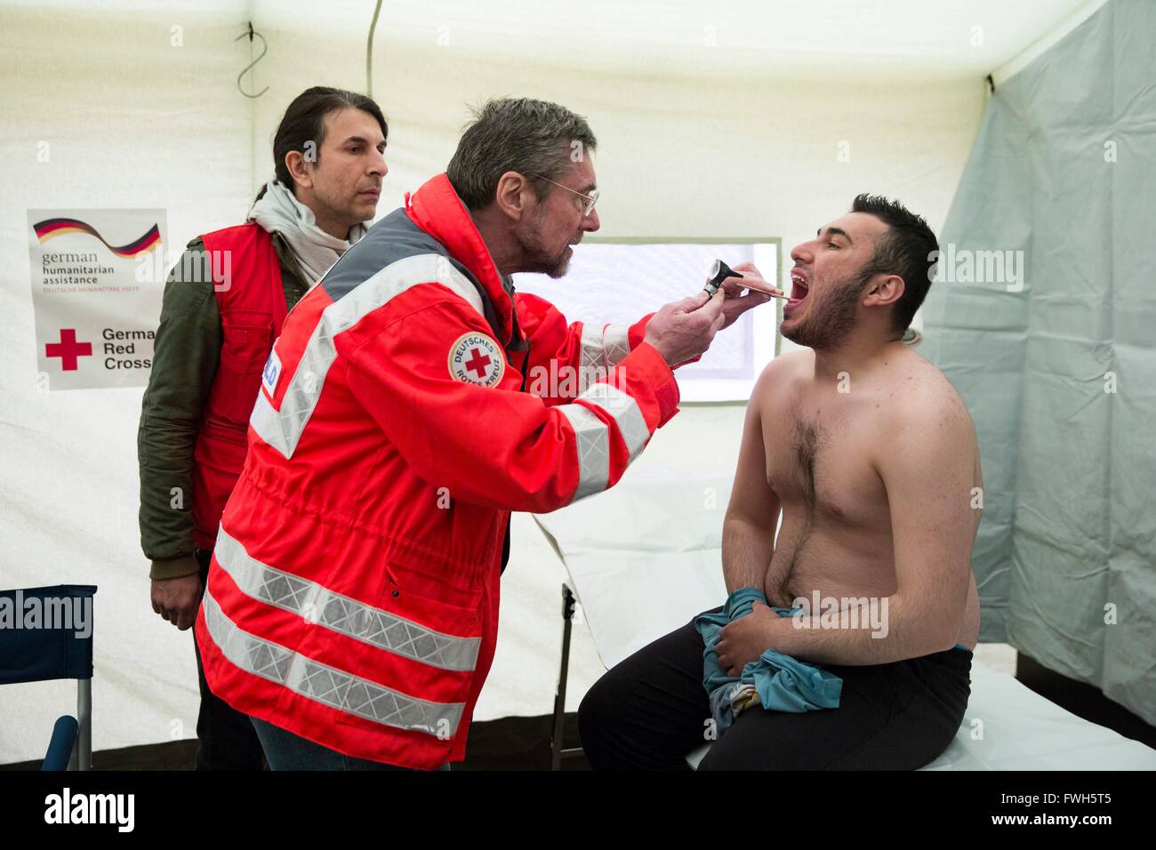 A German Red Cross doctor and a translator work in a basic health care ...