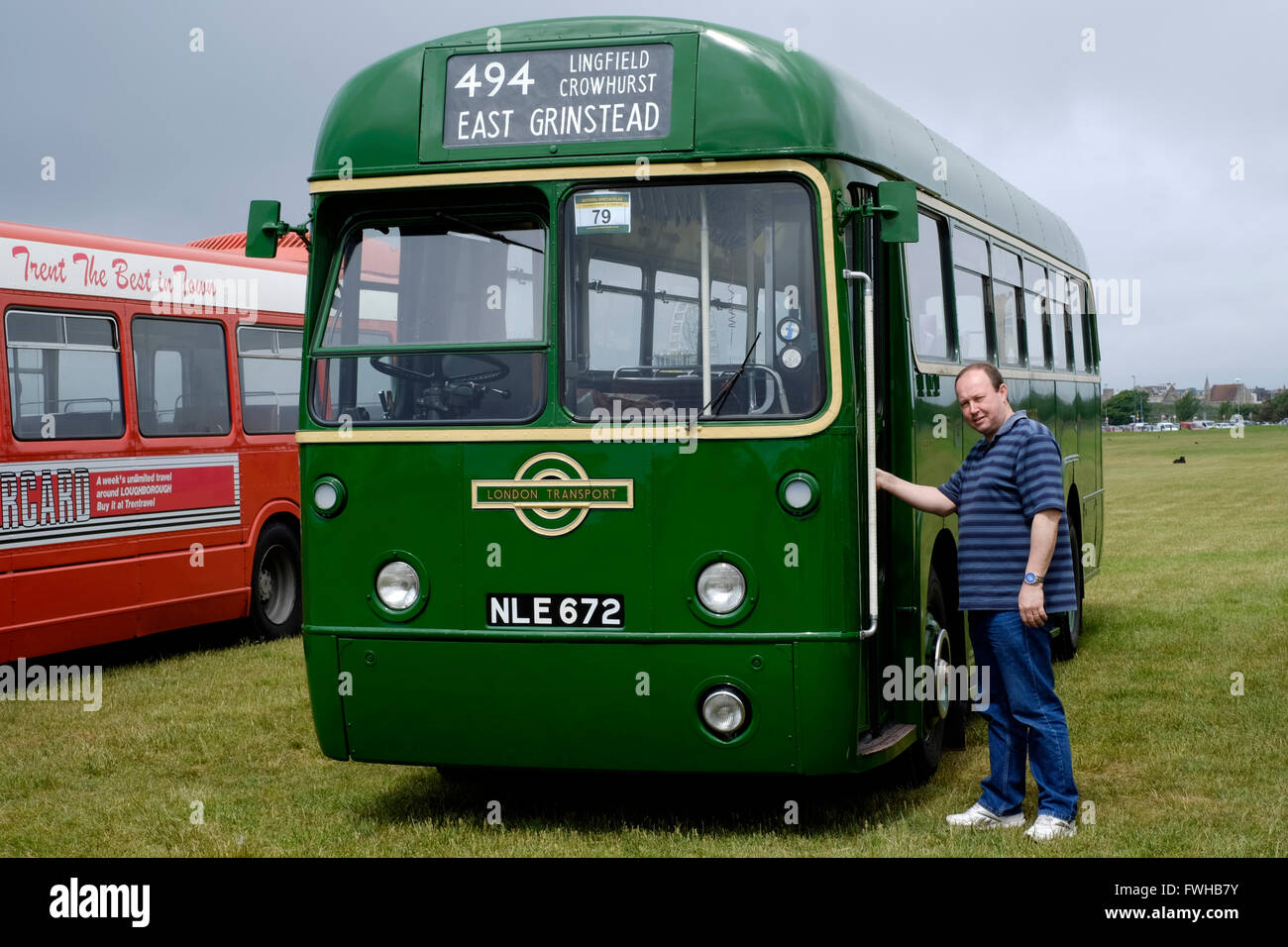 a man standing by his vehicle at a show of classic vintage buses ...