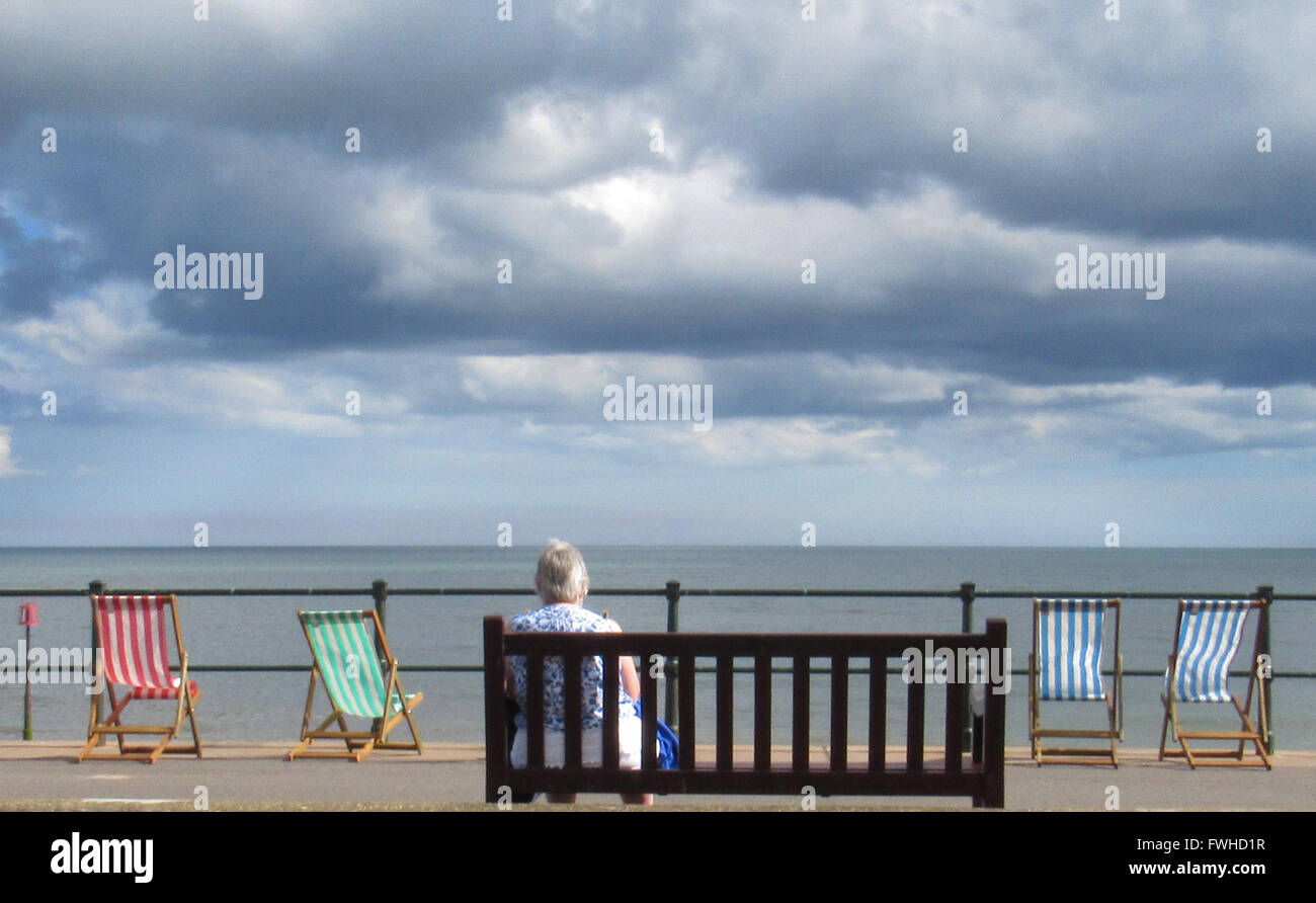 A lady on a seafront bench looks out to sea on Sidmouth Esplanade Stock ...
