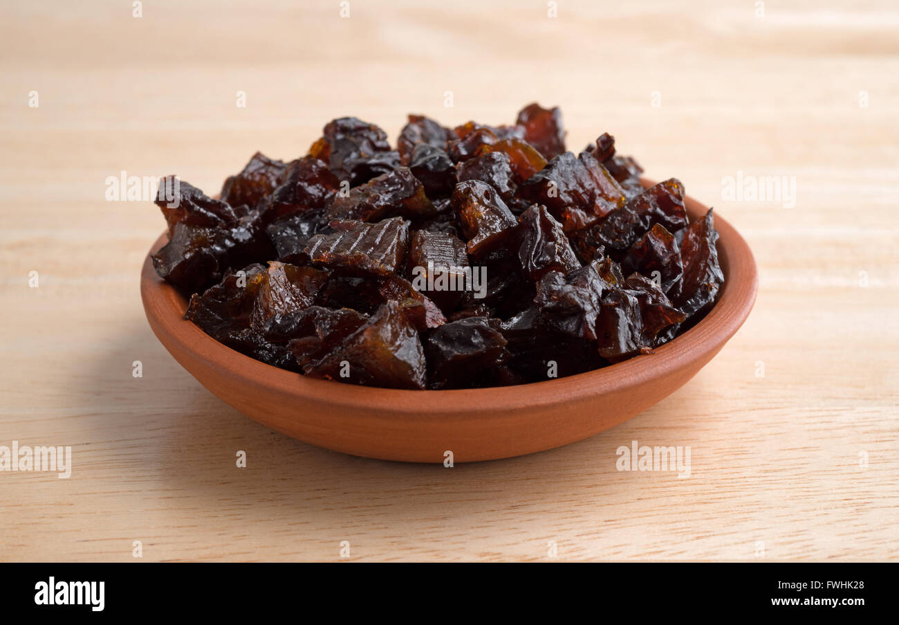 A portion of diced prunes in a small bowl atop a wood table top Stock ...