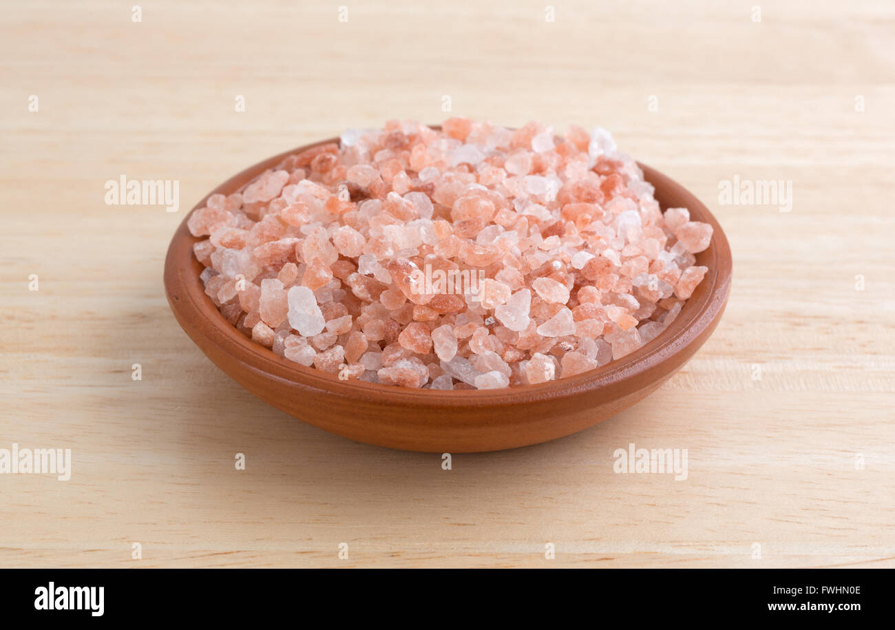 A portion of Himalayan pink salt in a small bowl on a wood table top ...