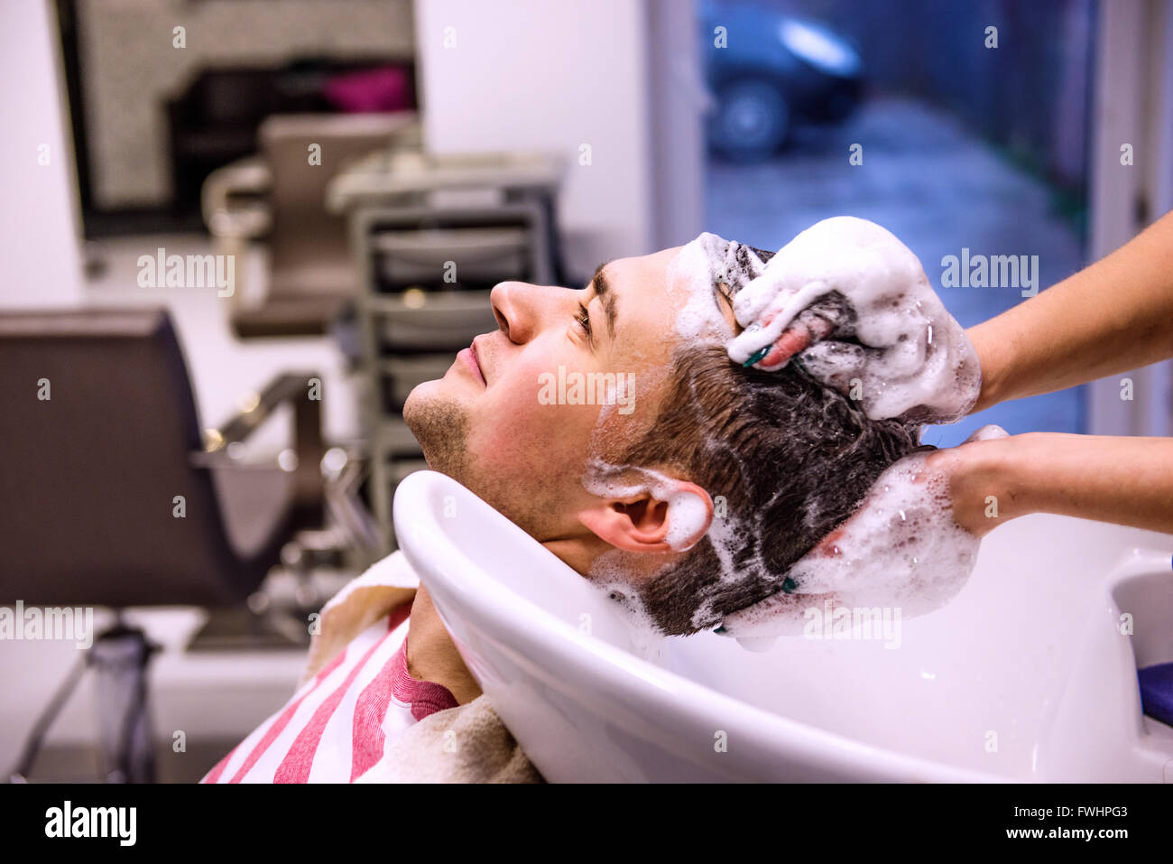 Professional hairdresser washing hair to her handsome client Stock ...