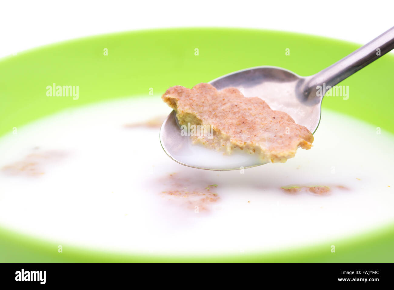 spoon taking out a soaking cracker from bowl of milk with clipping path ...