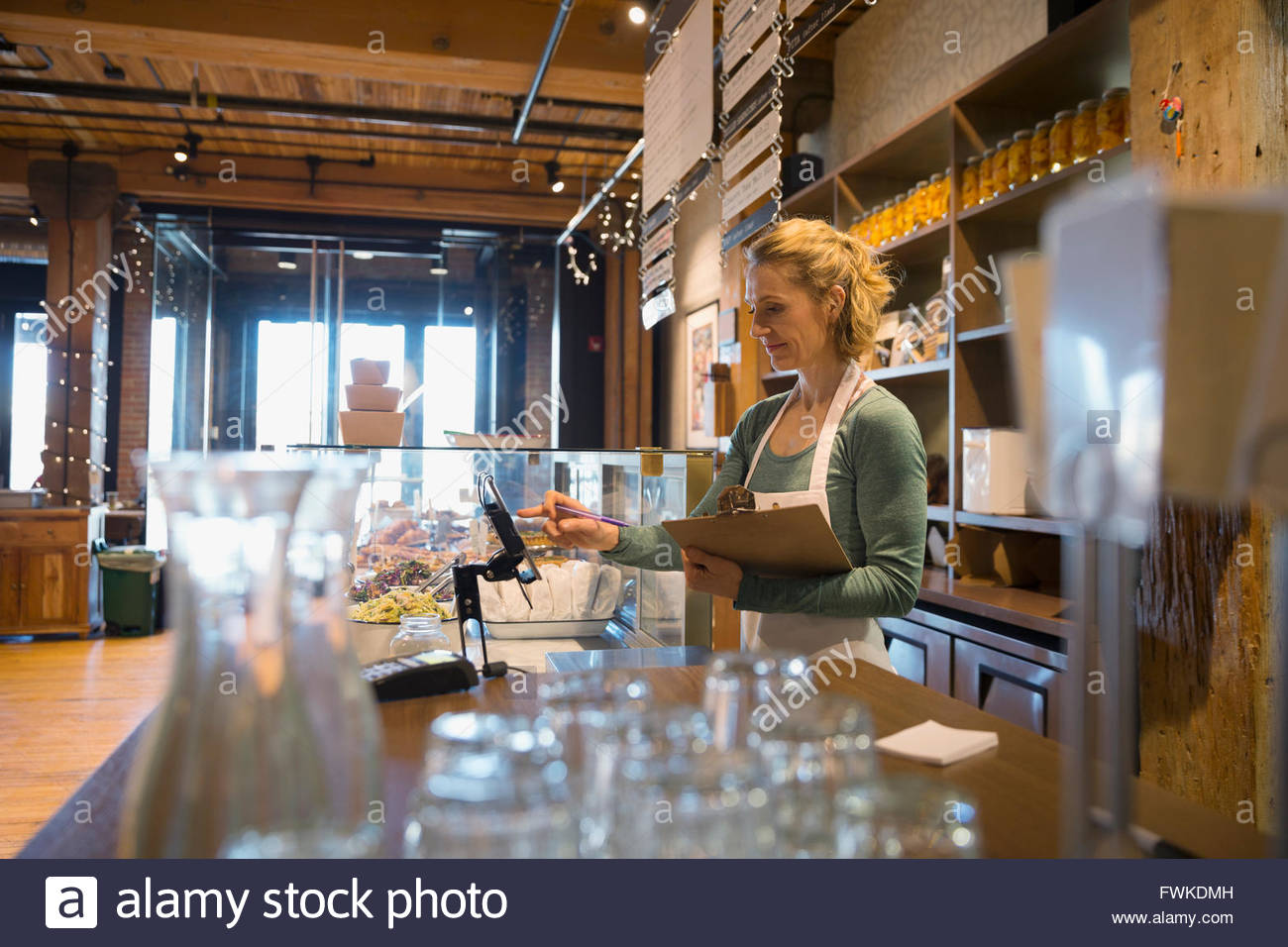 Bakery owner with clipboard at cash register Stock Photo - Alamy