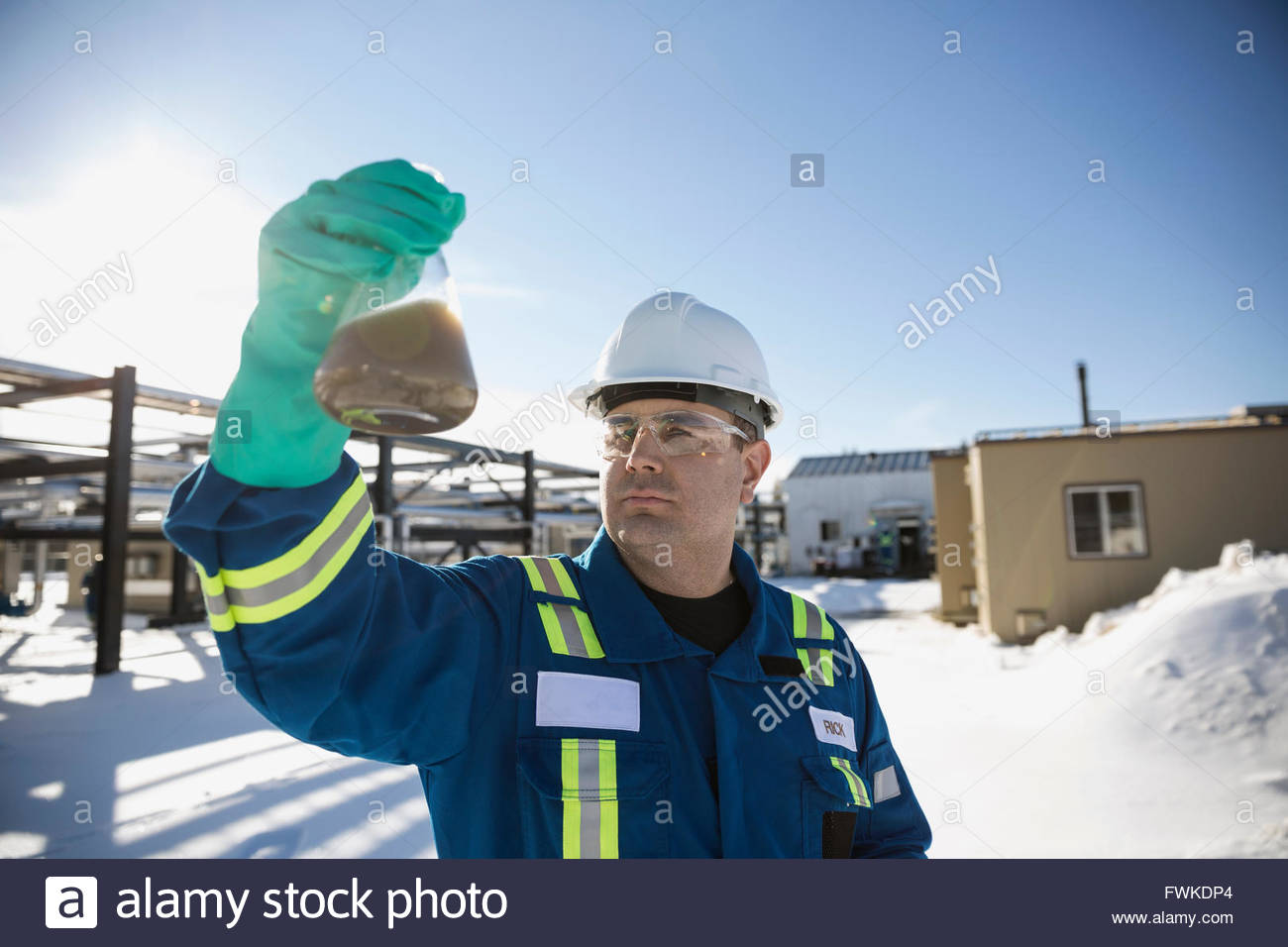 Male engineer examining liquid in beaker gas plant Stock Photo - Alamy