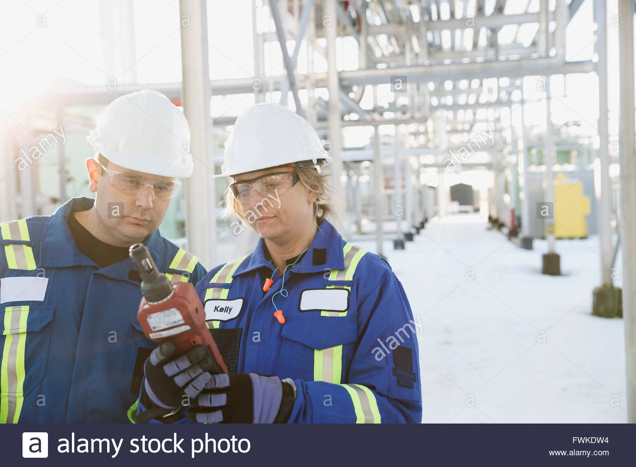 Workers using testing equipment at snowy gas plant Stock Photo - Alamy