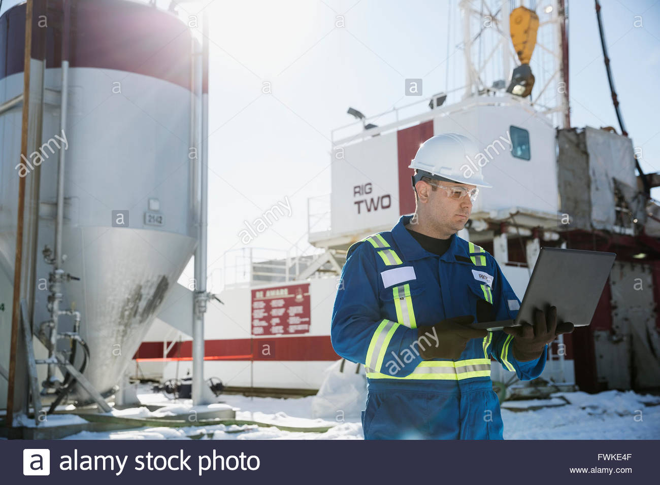 Male engineer using laptop below drilling rig Stock Photo - Alamy