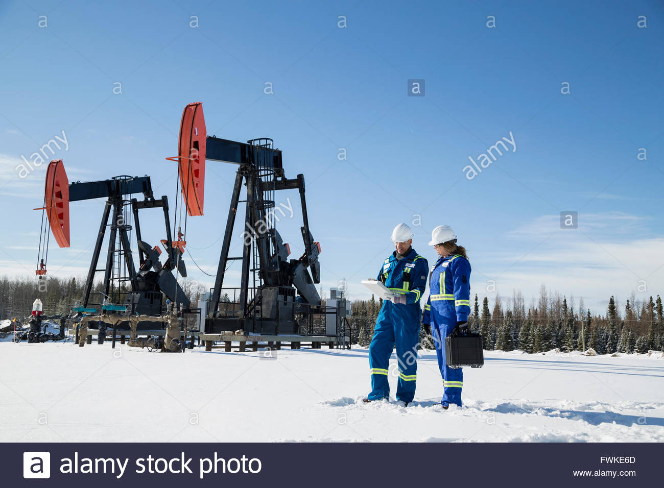 Workers discussing paperwork at drilling rigs in snow Stock Photo - Alamy