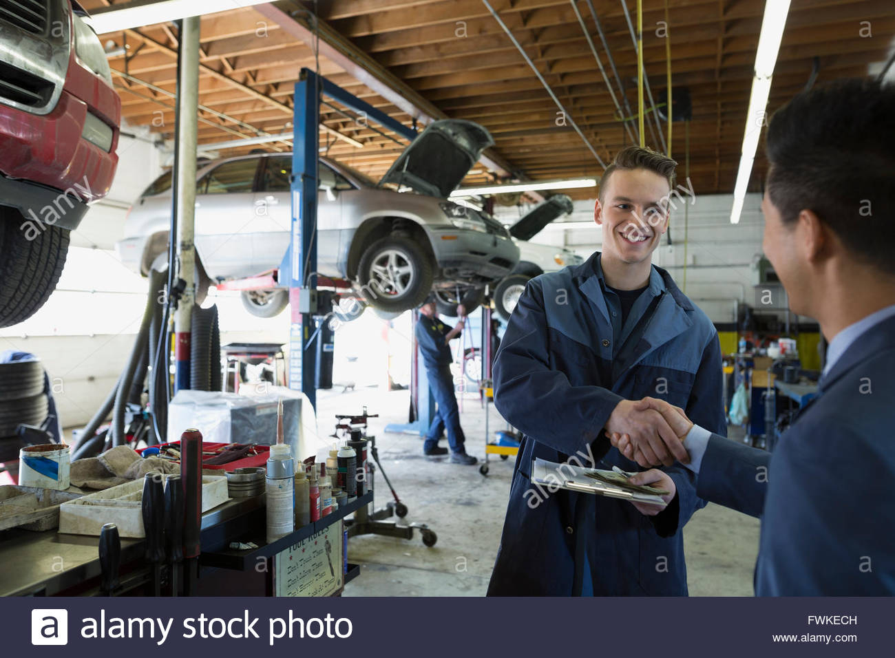 Mechanic and customer shaking hands auto repair shop Stock Photo - Alamy