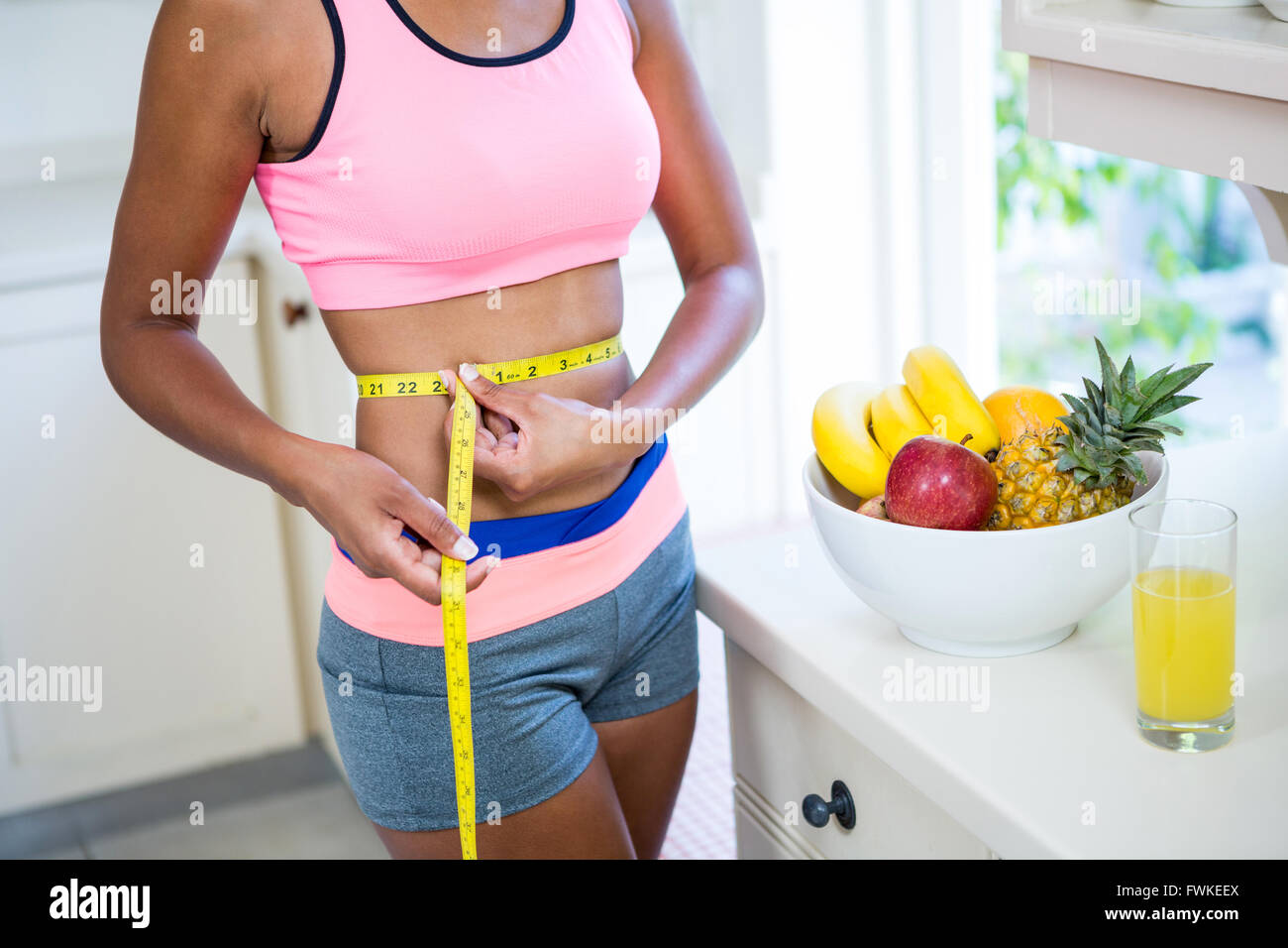 Mid-section of woman measuring her waist Stock Photo - Alamy