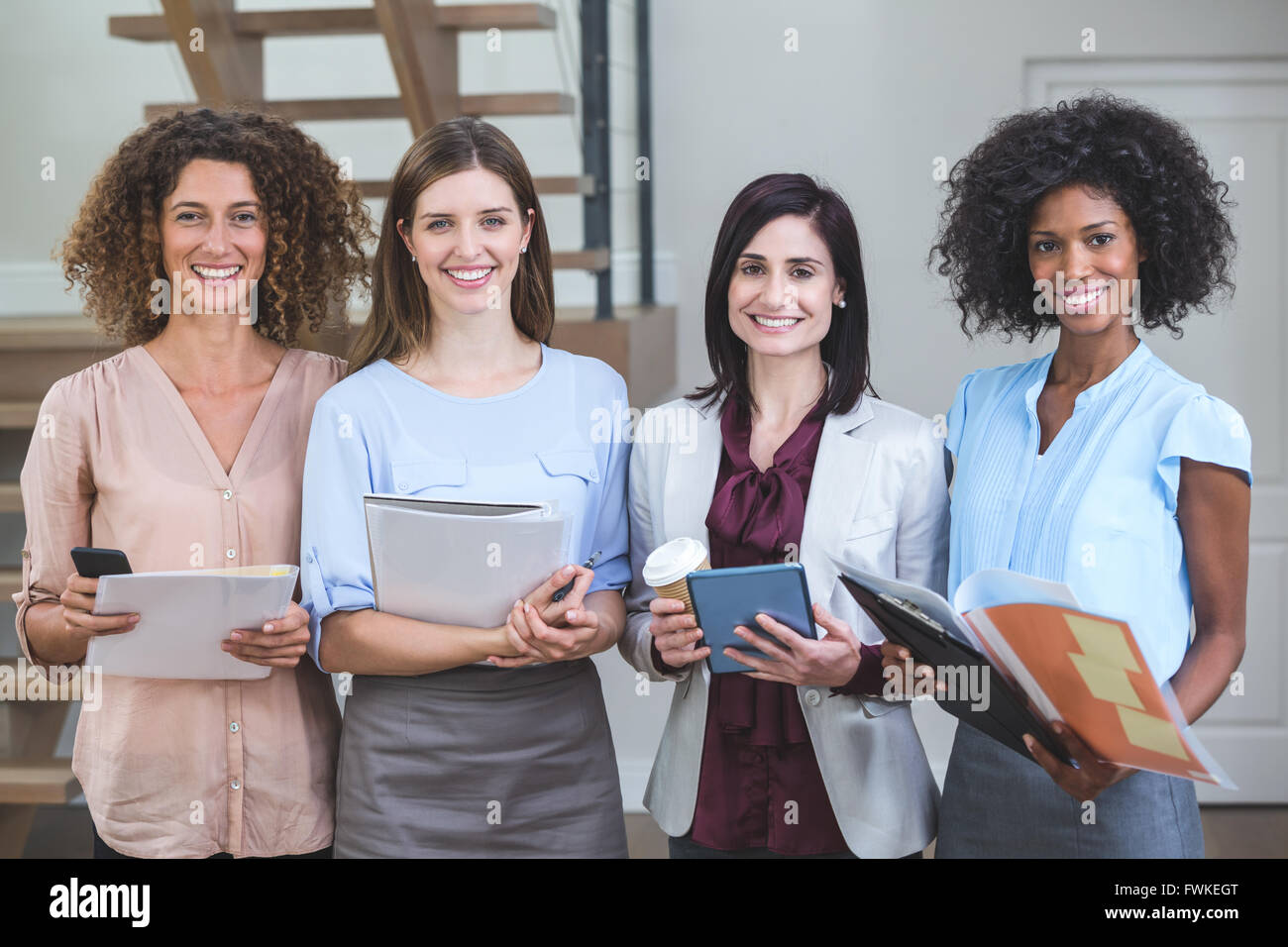 Portrait of female business colleagues standing together with file and ...