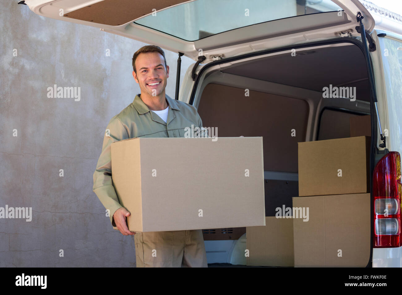 Happy delivery man carrying a cardboard box Stock Photo - Alamy