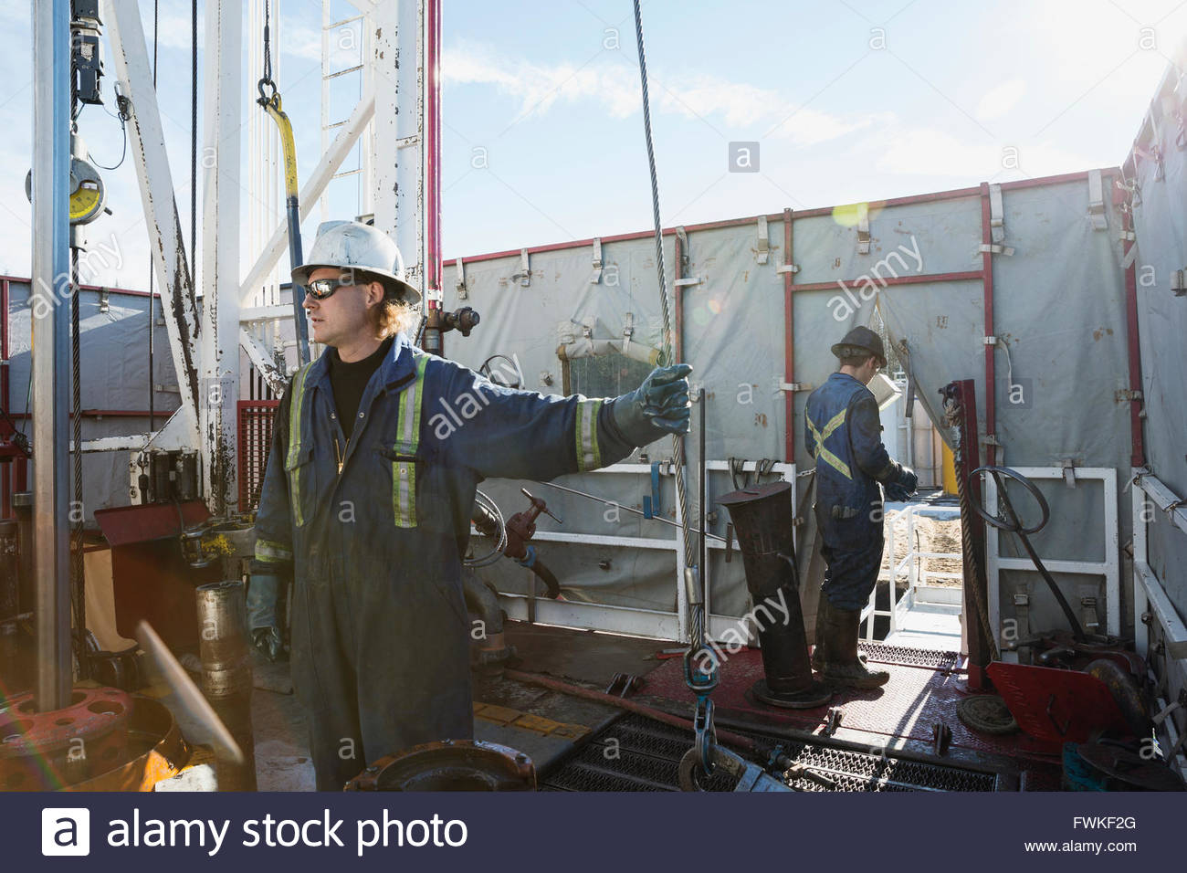 Male workers working drilling rig at gas plant Stock Photo - Alamy