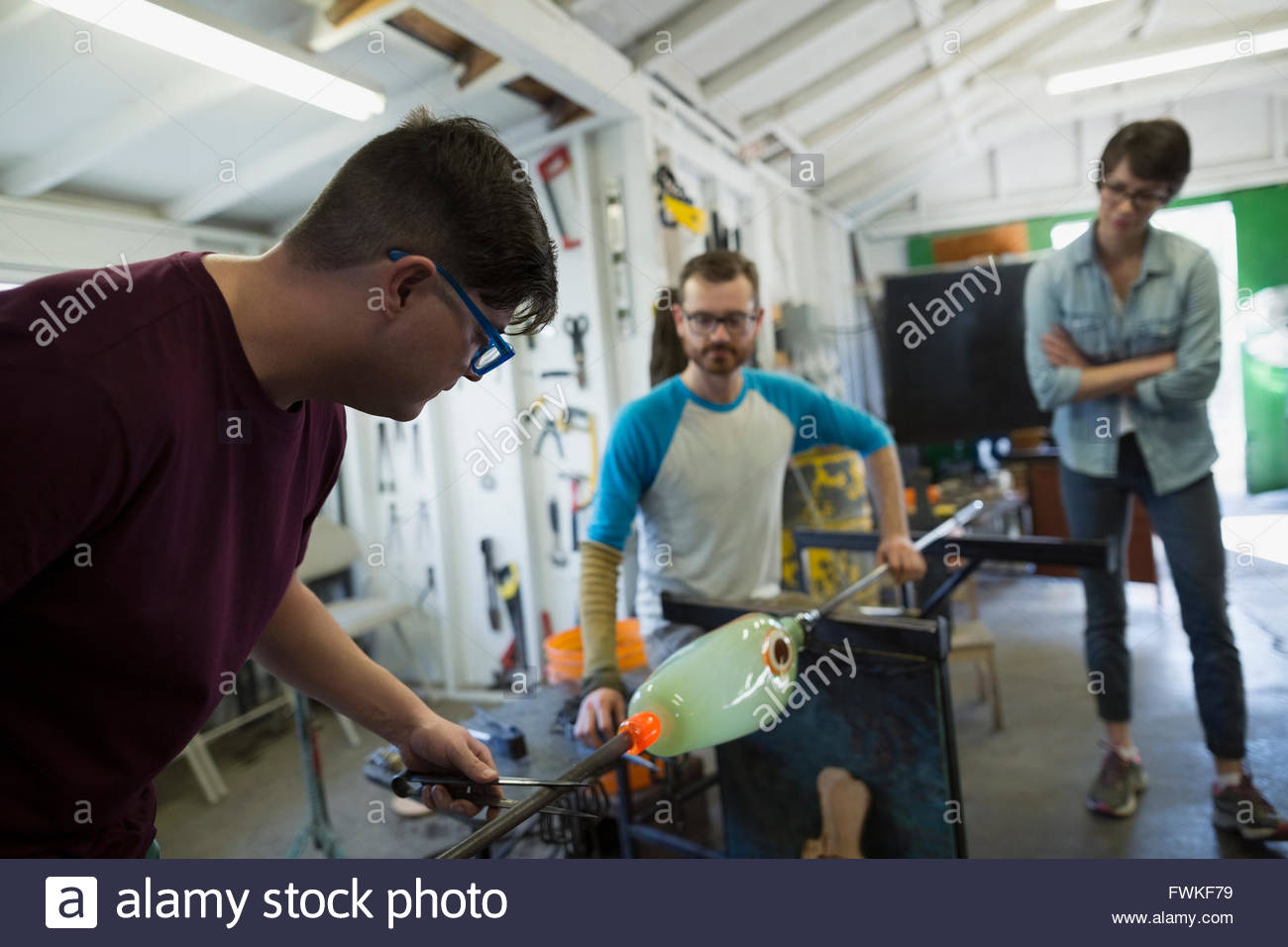 Glassblowers shaping molten glass in workshop Stock Photo - Alamy