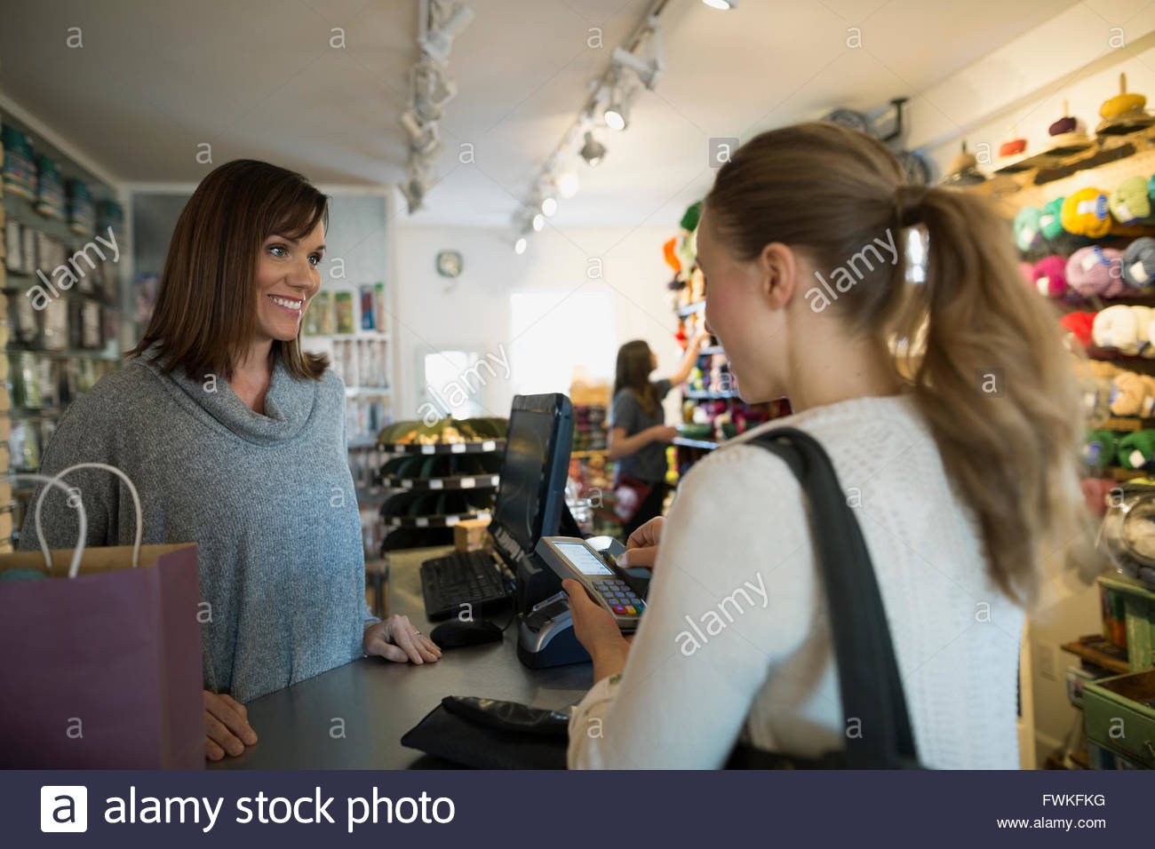 Yarn store owner shopper paying credit card machine Stock Photo - Alamy