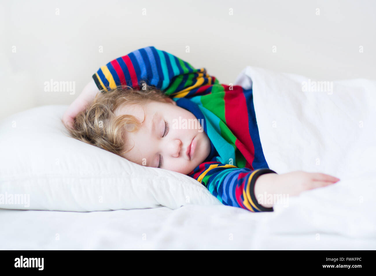 Adorable toddler girl taking a nap in a white sunny bedroom Stock Photo ...