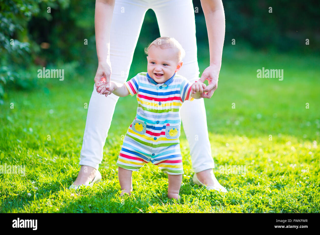 Cute funny happy baby in a colorful shirt making his first steps on a ...