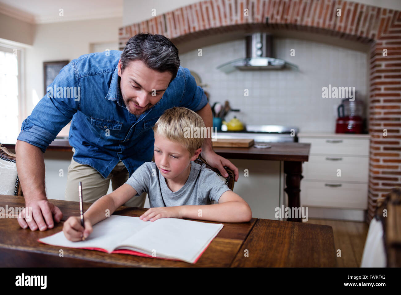 Father helping son with his homework in kitchen Stock Photo - Alamy