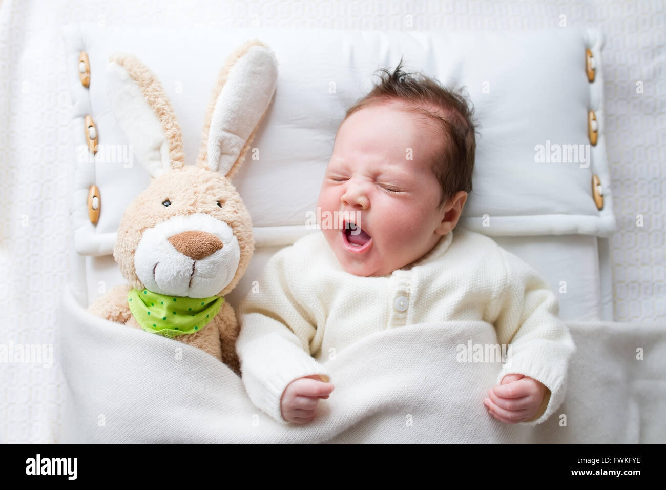 Adorable sleepy newborn baby with a toy bunny yawning in bed Stock ...