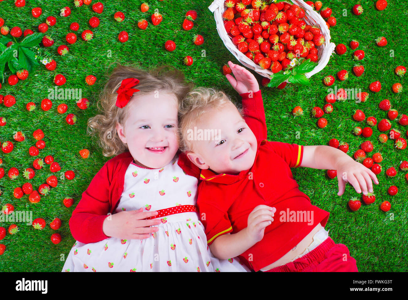 Child eating strawberry. Little girl and baby boy play and eat fresh ...