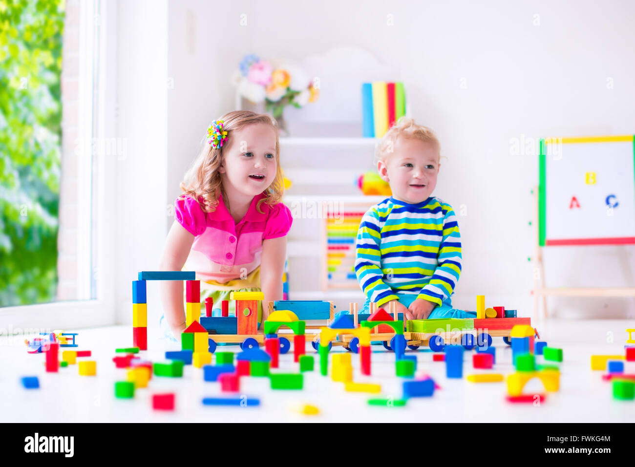 Kids play at day care. Two toddler children build tower of colorful ...