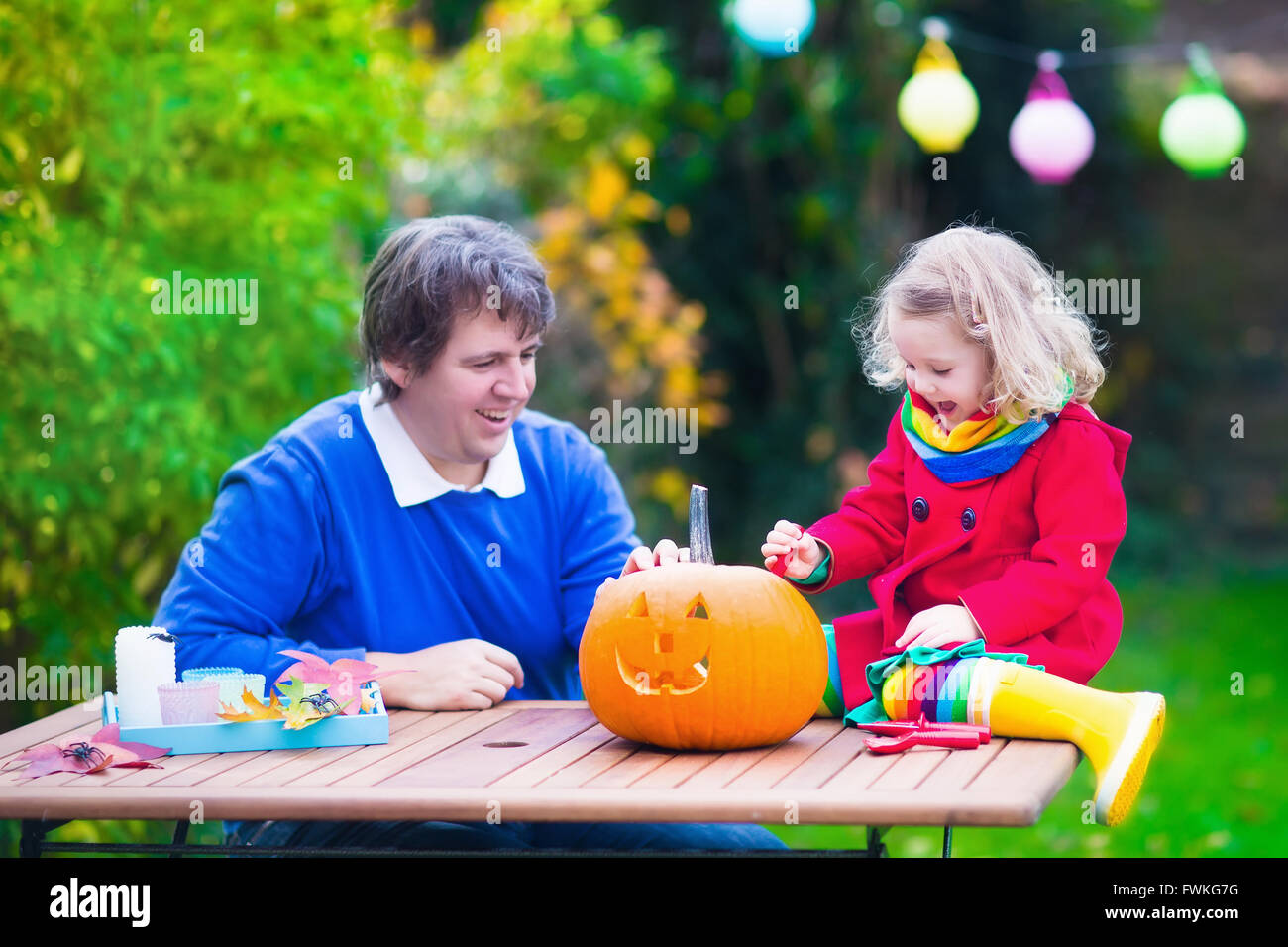 Family carving pumpkin at Halloween. Dressed up child trick or treating ...