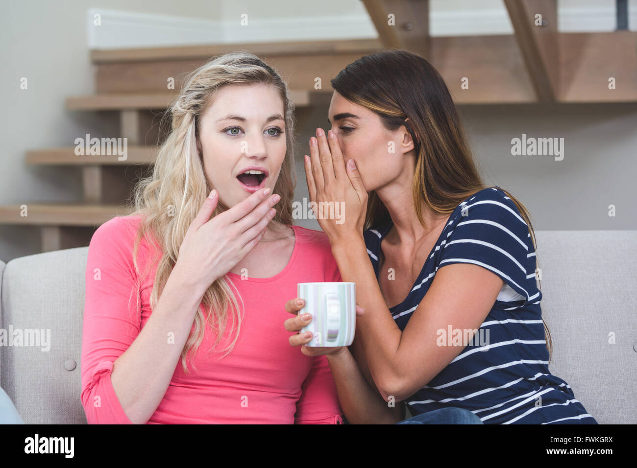 Young woman whispering a secret to her friend Stock Photo - Alamy