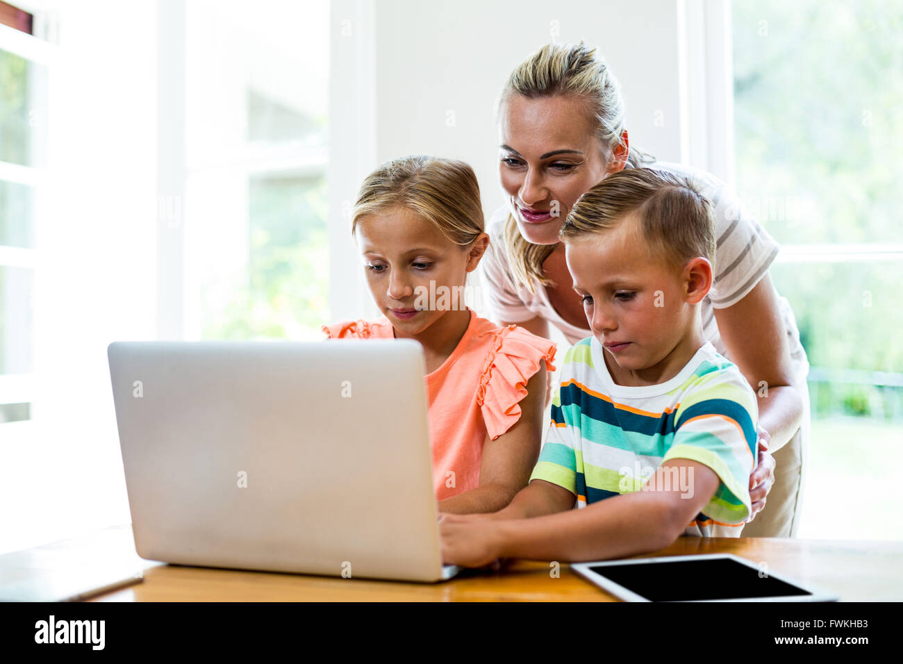 Mother teaching children to use laptop at home Stock Photo - Alamy