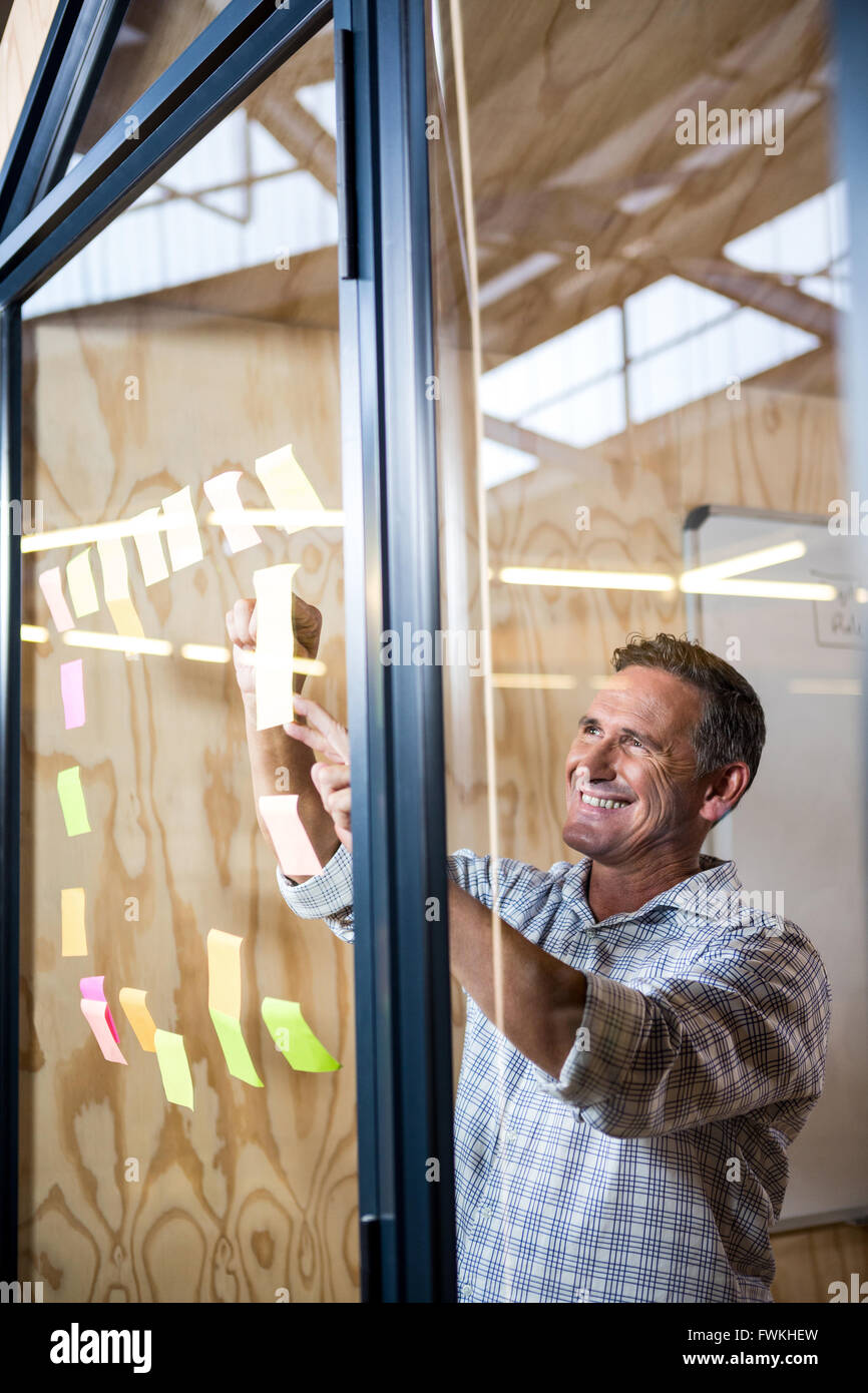 Man looking at sticky notes on window Stock Photo - Alamy