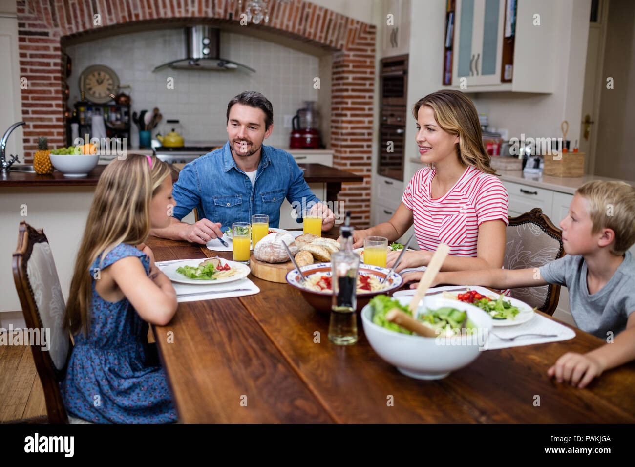 Happy family talking to each other while having meal in kitchen Stock ...