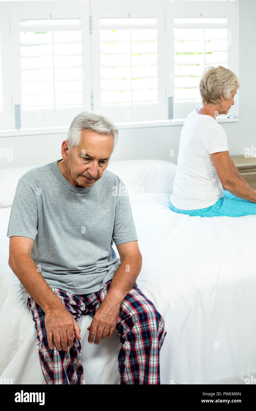 Sad aged man sitting on bed with woman Stock Photo - Alamy