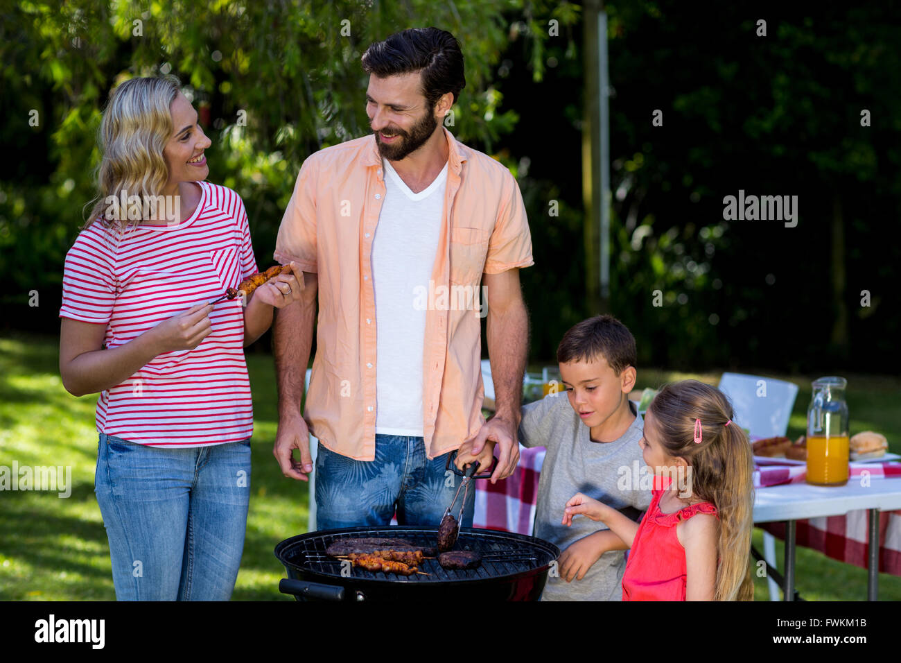 Mother and father with children cooking food at barbecue Stock Photo ...