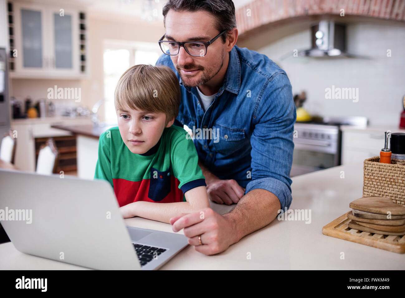 Father and son using laptop in kitchen Stock Photo - Alamy