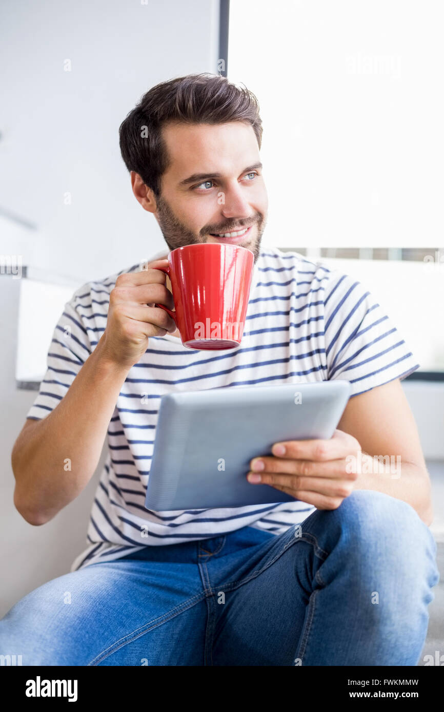 Happy man holding digital tablet while having cup of coffee Stock Photo ...