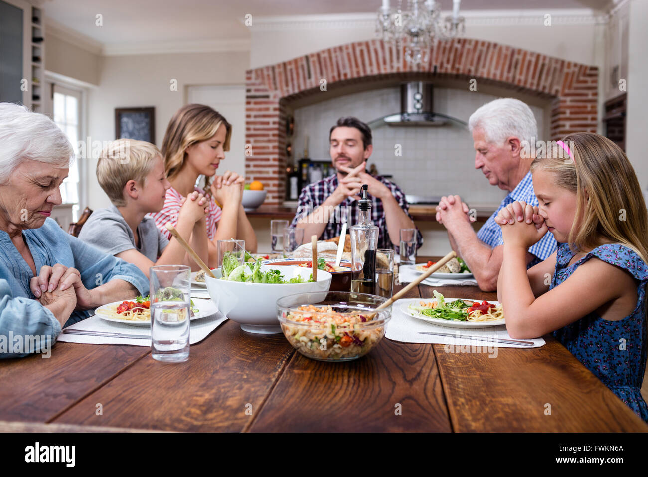 Multi-generation family praying before having meal Stock Photo - Alamy