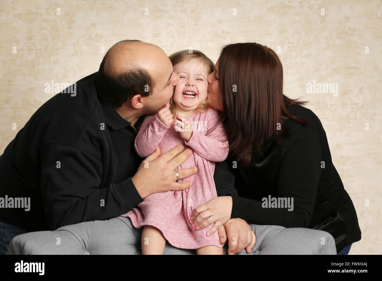 Parents kissing their child Stock Photo - Alamy