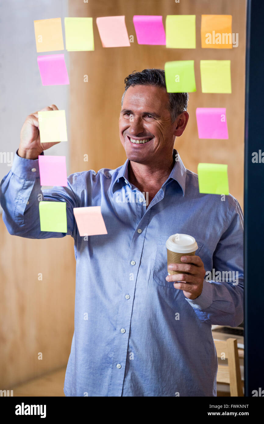 Man writing on sticky notes and holding coffee Stock Photo - Alamy