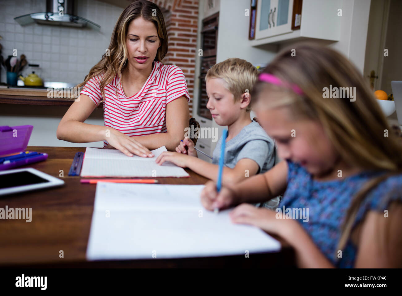 Mother helping kids with their homework Stock Photo - Alamy