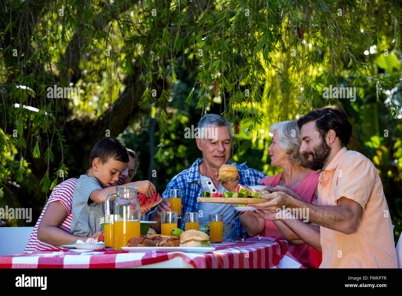 Happy family enjoying while having food in yard Stock Photo - Alamy